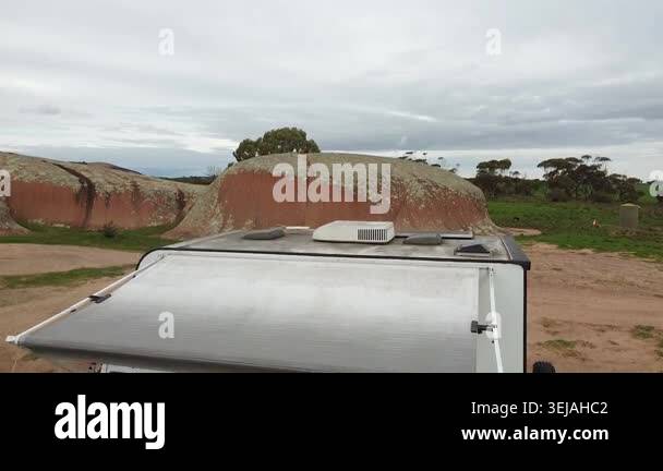 A camper is parked near rust-colored sandstone domes in a remote area ...