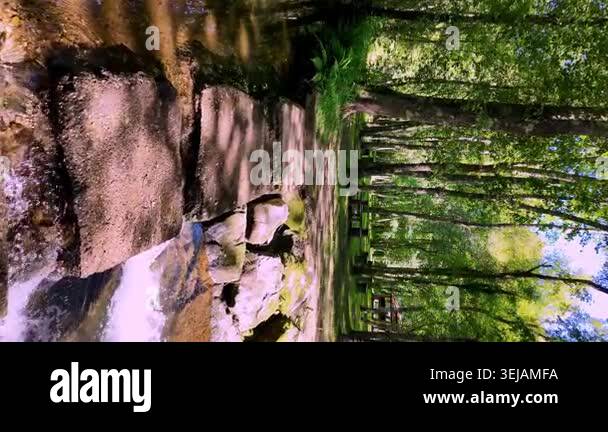 A drone flies over large stone steps across a creek, revealing a lush ...