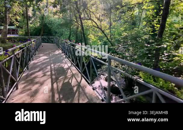A concrete footbridge with a metal railing decorated with pink flowers ...