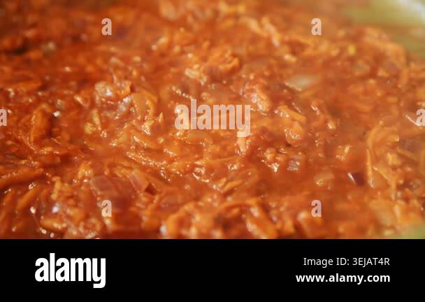 Hands stirring rich red tomato sauce blended with soft onions and ...