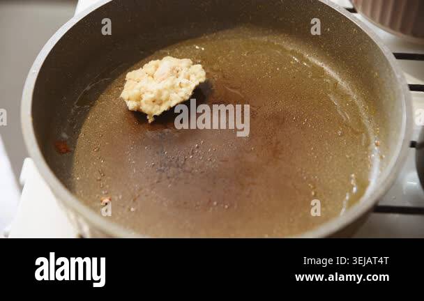 Pale fish patties carefully arranged in nonstick frying pan on gas ...