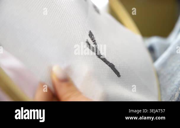 Detailed view of hand carefully embroidering black cross stitch pattern ...