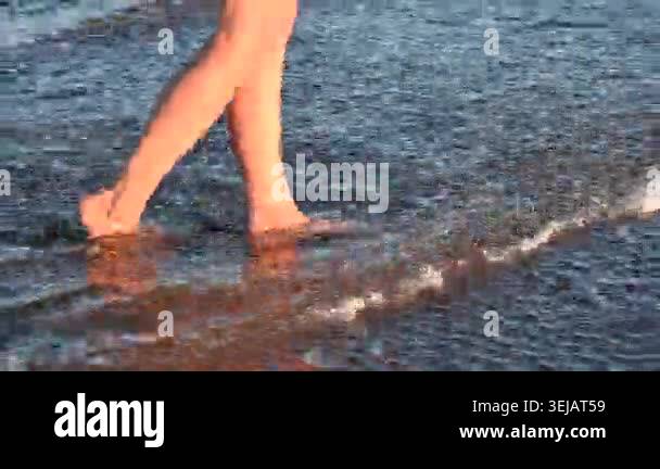 sea foam and sea wave, Barefoot person walking on wet sand beside the ...