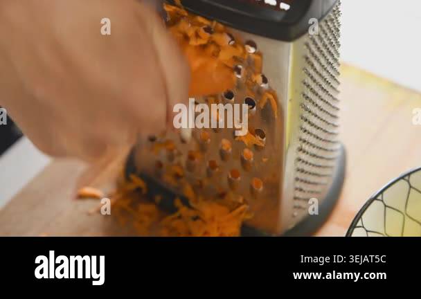 Close hand motion grating fresh orange vegetable finely using stainless ...