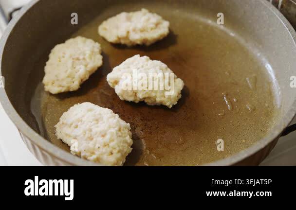 Freshly shaped fish patties placed carefully in heated frying pan cook ...