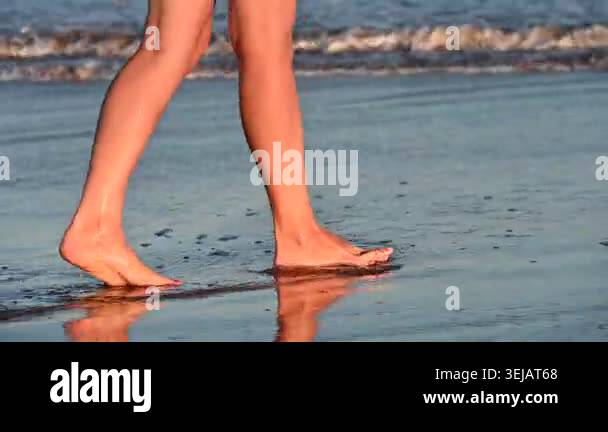 sea foam and sea wave, Barefoot person walking on wet sand beside the ...