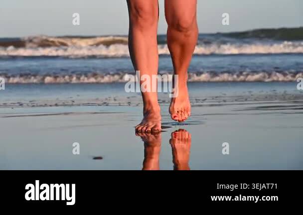 sea foam and sea wave, Barefoot person walking on wet sand beside the ...