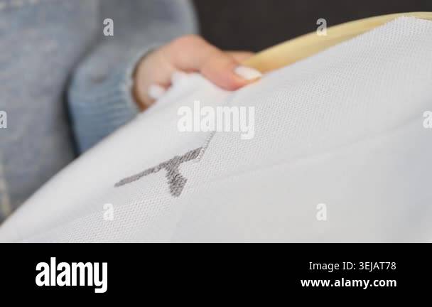 Close up view of hands stitching black thread cross stitch pattern on ...
