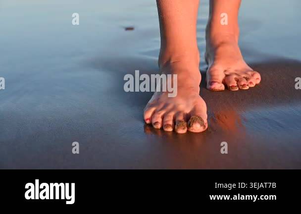 sea foam and sea wave, Barefoot person walking on wet sand beside the ...