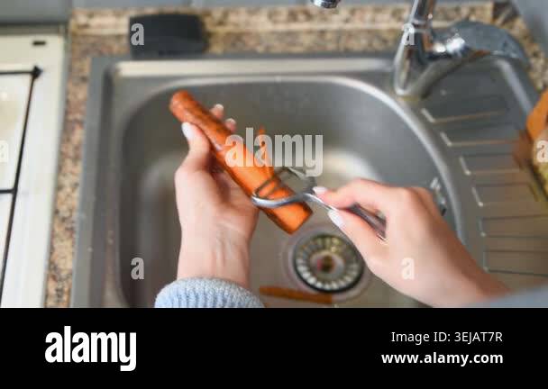 Person using shiny metal vegetable peeler to remove skin from vibrant ...