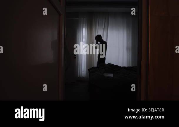 Doorway silhouette man standing near bed, traveler in hotel or small ...