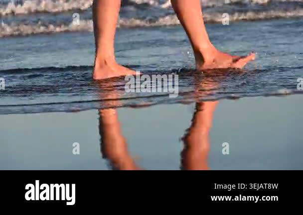 sea foam and sea wave, Barefoot person walking on wet sand beside the ...