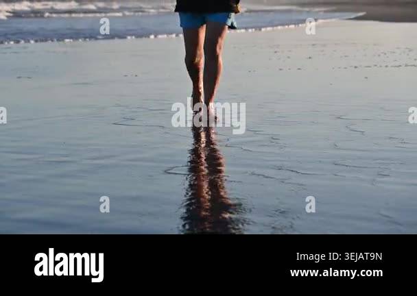 sea foam and sea wave, Barefoot person walking on wet sand beside the ...