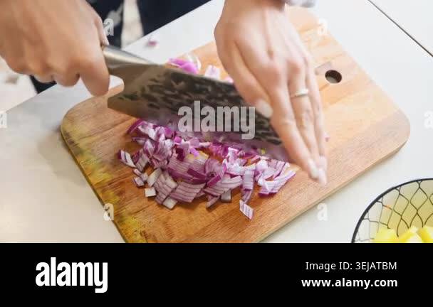 Close up view of precise knife cutting hand dicing vibrant red onion ...