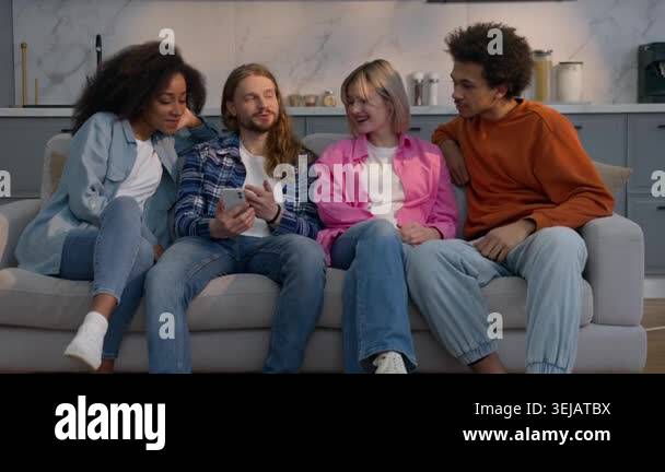 Caucasian man showing mobile phone picture video to multiethnic friends ...