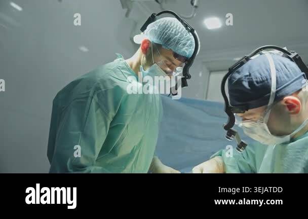 Two surgeons man suturing patient on operating table surgical procedure ...