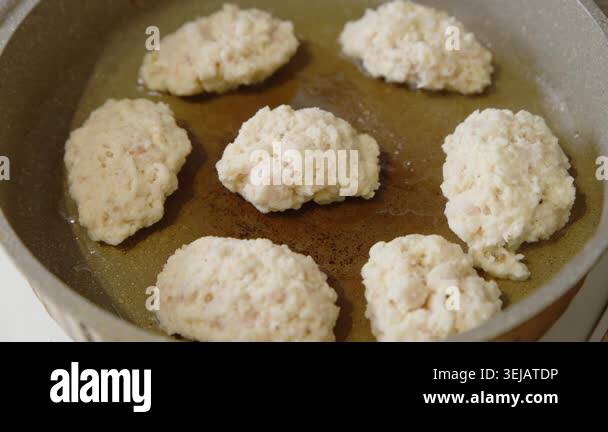 Handmade RAW fish patties frying gently in warm oil inside pan with ...