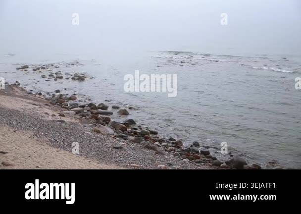 Foggy sea scene with rocky shore and gentle waves blending into misty ...