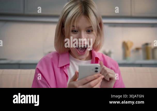 Happy excited amazed Caucasian woman at home celebrating win cellphone ...