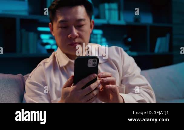 Concentrated serious Asian middle-aged man scrolling mobile phone ...