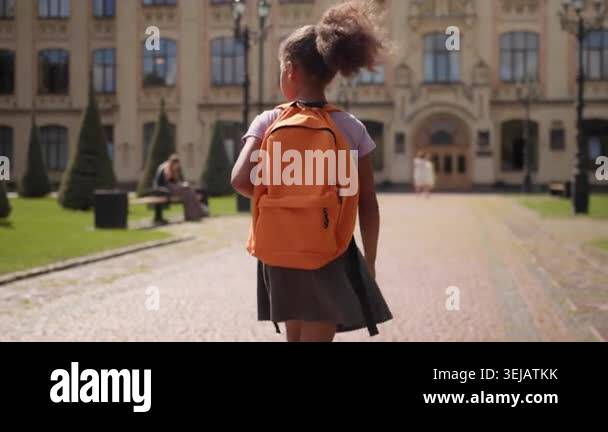 Back view African American little girl child with backpack walking go ...