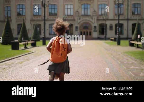 Back view African American little girl child with backpack running to ...