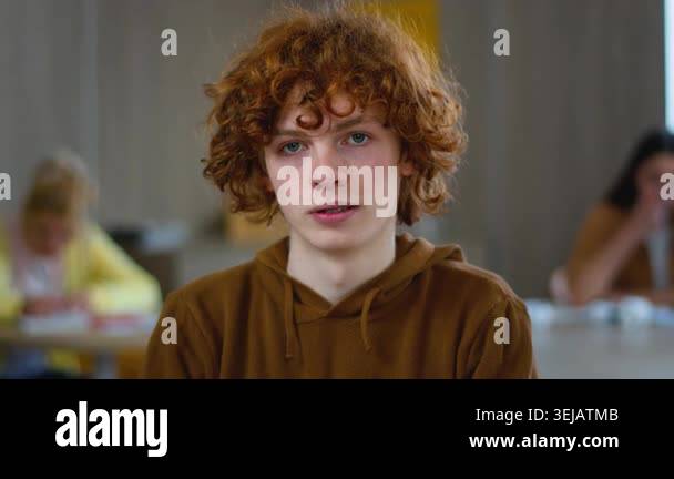 Serious ginger Caucasian boy student in high school looking at camera ...