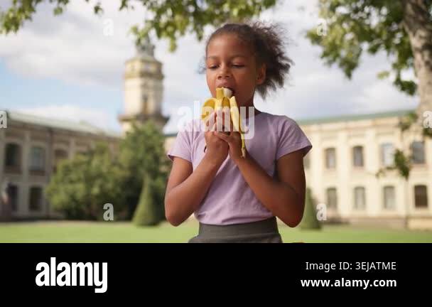 African American little girl happy child eating tasty banana outdoor ...