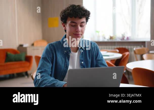 Smiling Caucasian male teenage school guy student using laptop studying ...