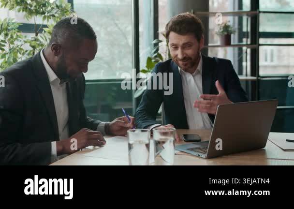 Two diverse multiracial business men team looking laptop laughing joke ...