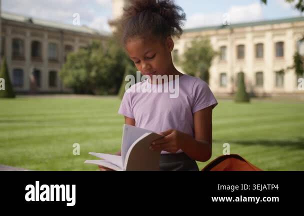 Pensive African American little girl kid learning reading book thinking ...