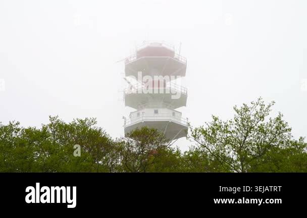 Tall lighthouse with red and white painted structure emerges softly ...