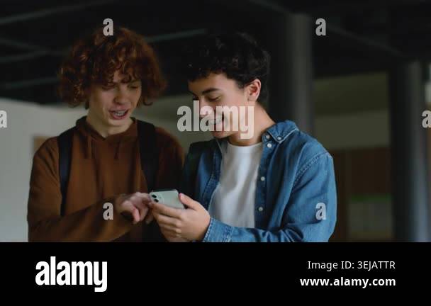 Caucasian two teens students guys friends talk smiling laughing using ...