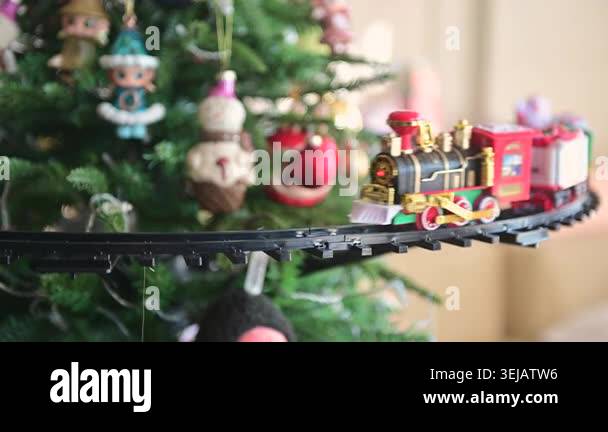 4K Toy train running on circular track around decorated christmas tree ...