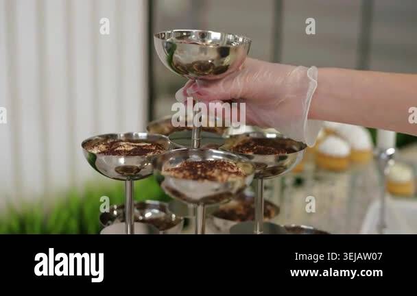 Professional catering worker arranging tiramisu portions at a luxury ...