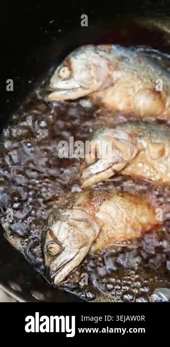 4K Vertical view of deep frying short mackerel in a pan with bubbling ...