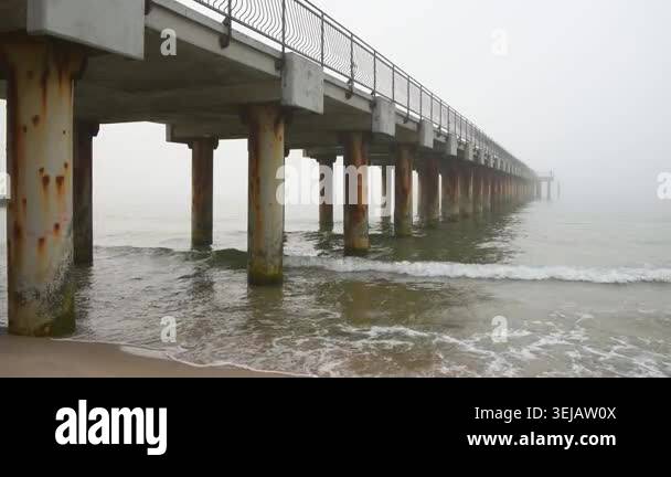 Long perspective view of aged pier with rusted pillars disappearing ...
