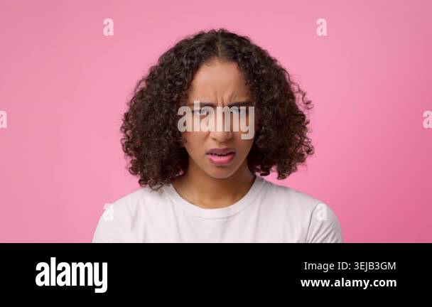 A young African American woman with curly hair shows a confused ...
