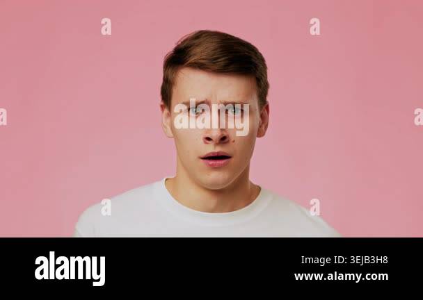 A young man stands facing the camera with a surprised expression. He ...