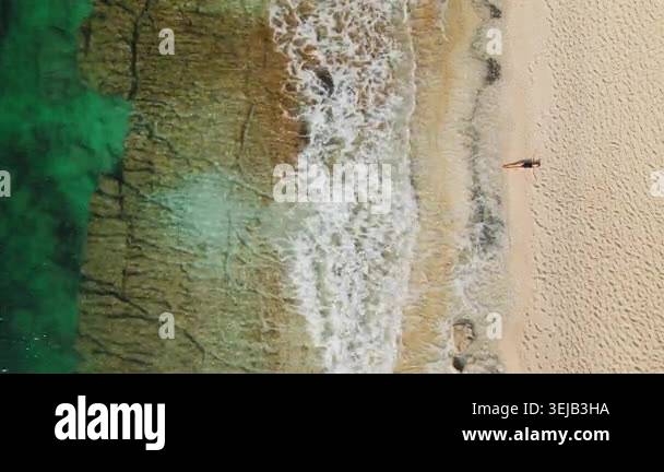 Aerial top view of beach and sea with woman relaxing near shoreline ...