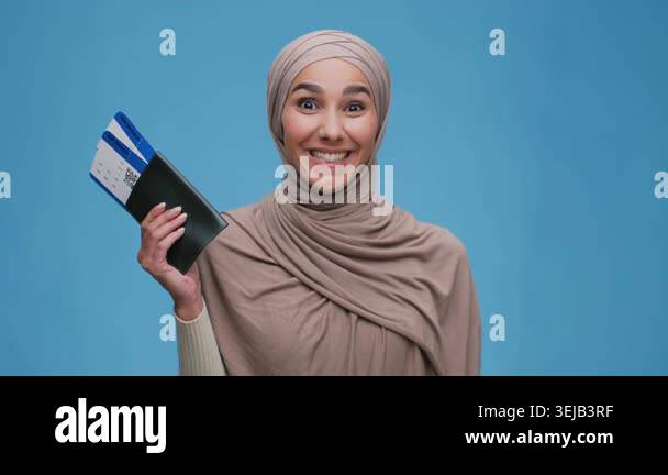 A woman smiles widely while holding a passport and a boarding ticket ...