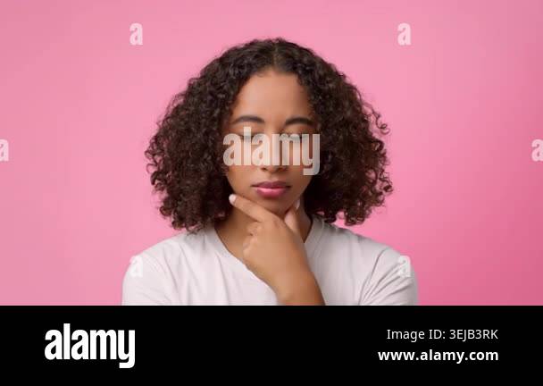 A woman with curly hair stands with her eyes closed, resting her chin ...