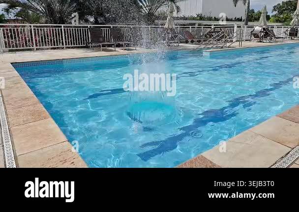 A soccer ball filled with water falls into the pool making a big splash ...