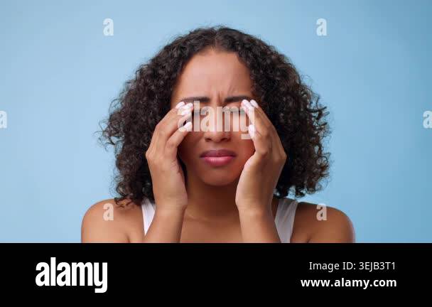 A woman with curly hair is pressing her hands against her face ...