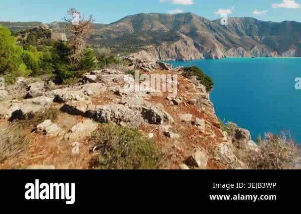 Rocky cliff and Assos Castle overlooking turquoise Ionian Sea in ...