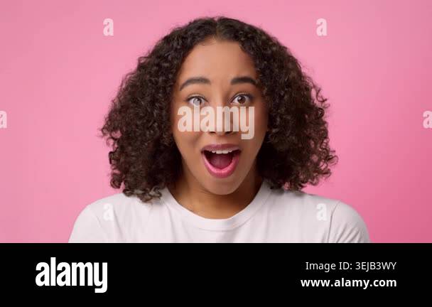 A young woman with curly hair shows a surprised expression, her mouth ...