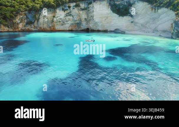 Aerial view of boat floating on turquoise waters near cliffs in ...
