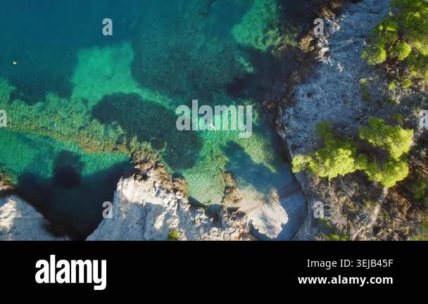Woman floats in calm cove surrounded by rocky cliffs and clear green ...