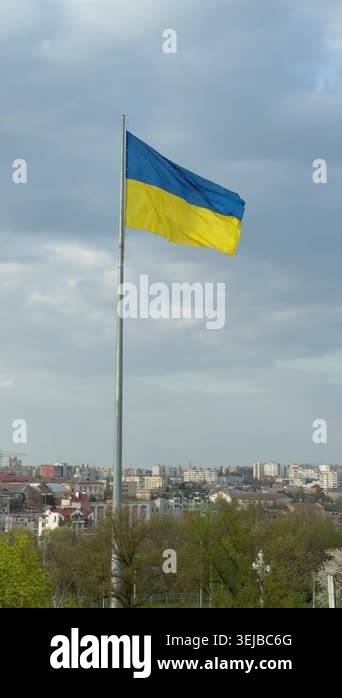 Ukrainian flag is flying on tall flagpole against the sky in Vinnytsia ...