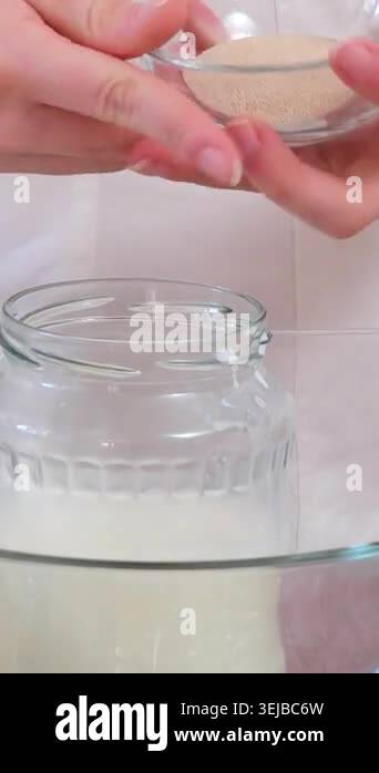 female pastry chef pours dry yeast into glass jar and carefully mixes ...